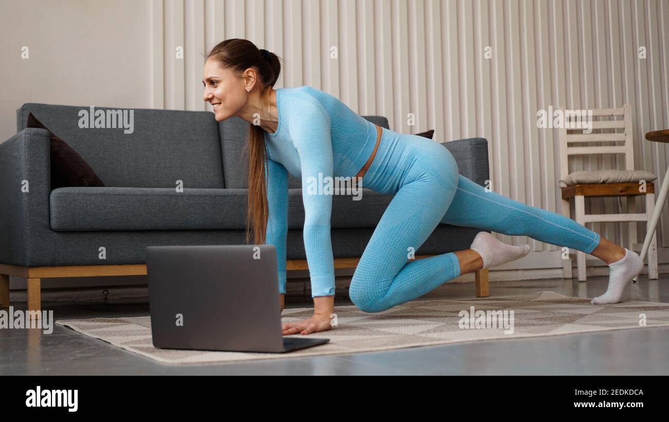 Beautiful young woman in a blue suit doing fitness exercise at home ...