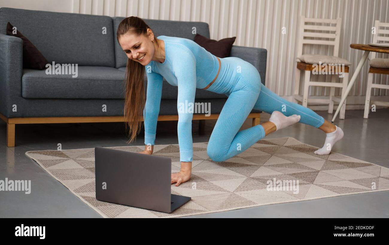 Beautiful young woman in a blue suit doing fitness exercise at home ...