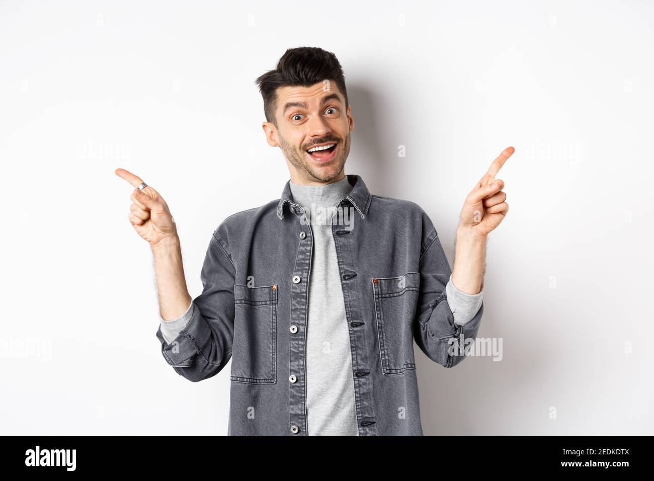 Cheerful smiling man pointing fingers sideways, showing left and right ...
