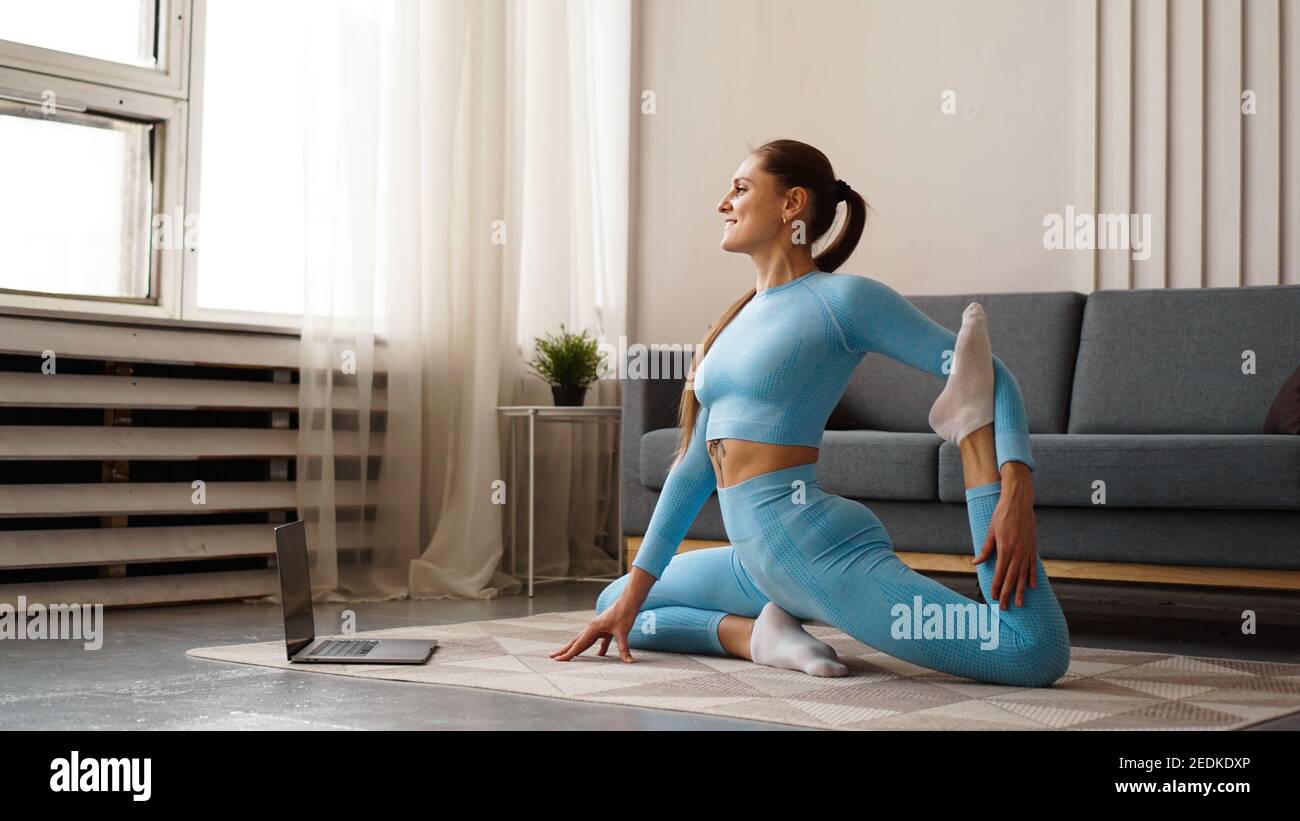 Beautiful young woman in a blue suit doing fitness exercise at home ...