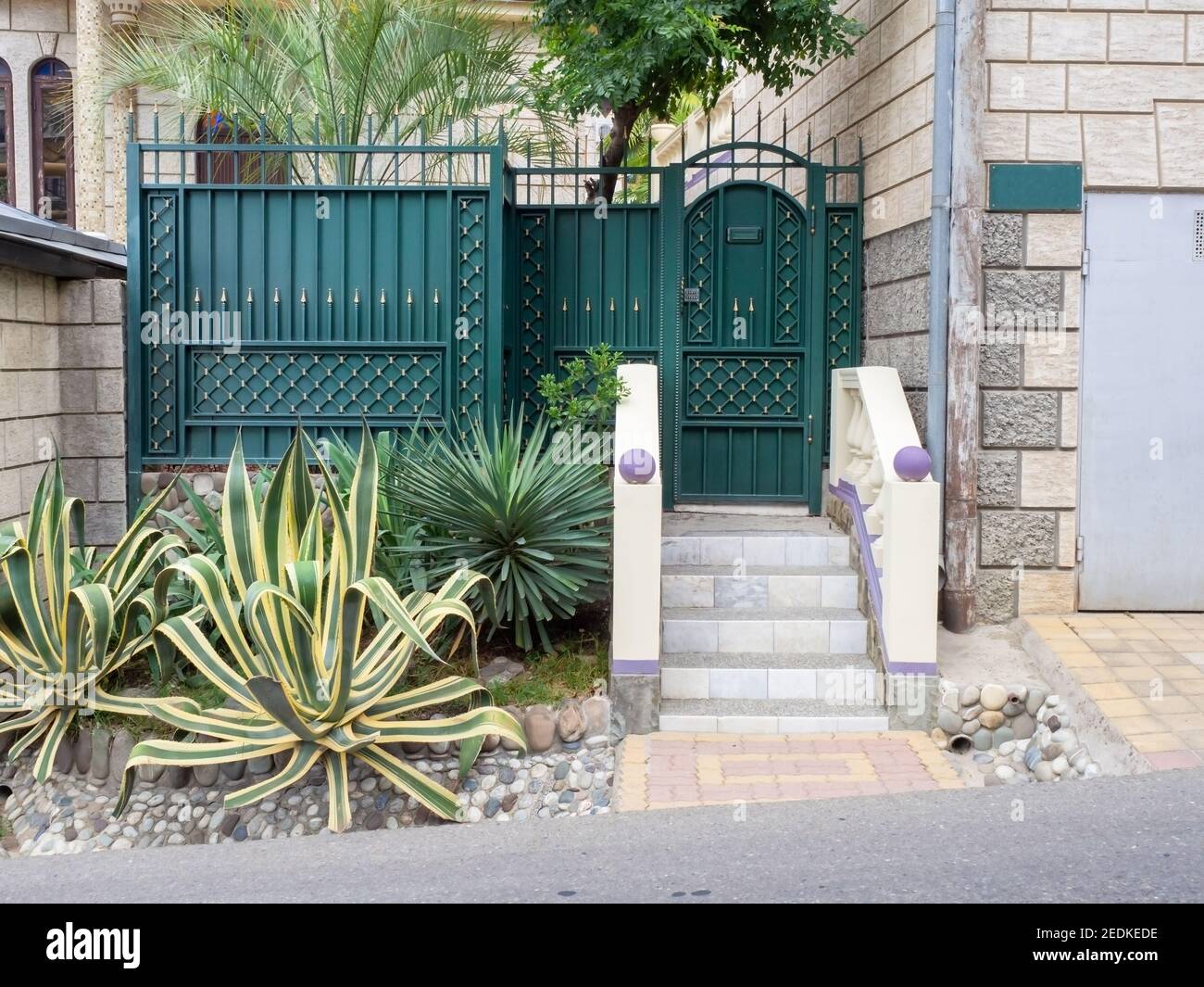 A dark turquoise decorative fence with wicket gate with marble steps ...