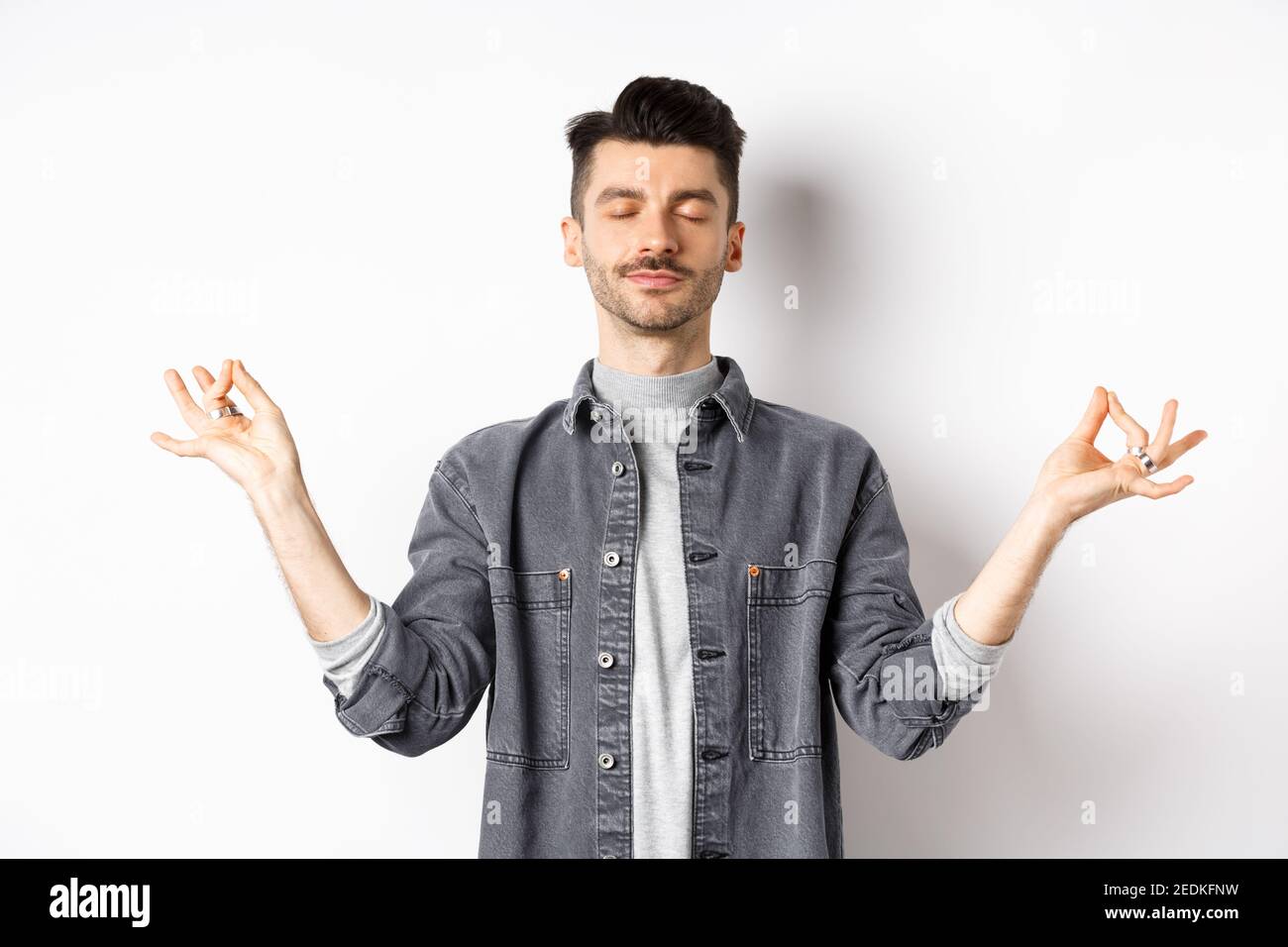 Calm guy meditating with peaceful face, holding hands in zen mudra sign ...