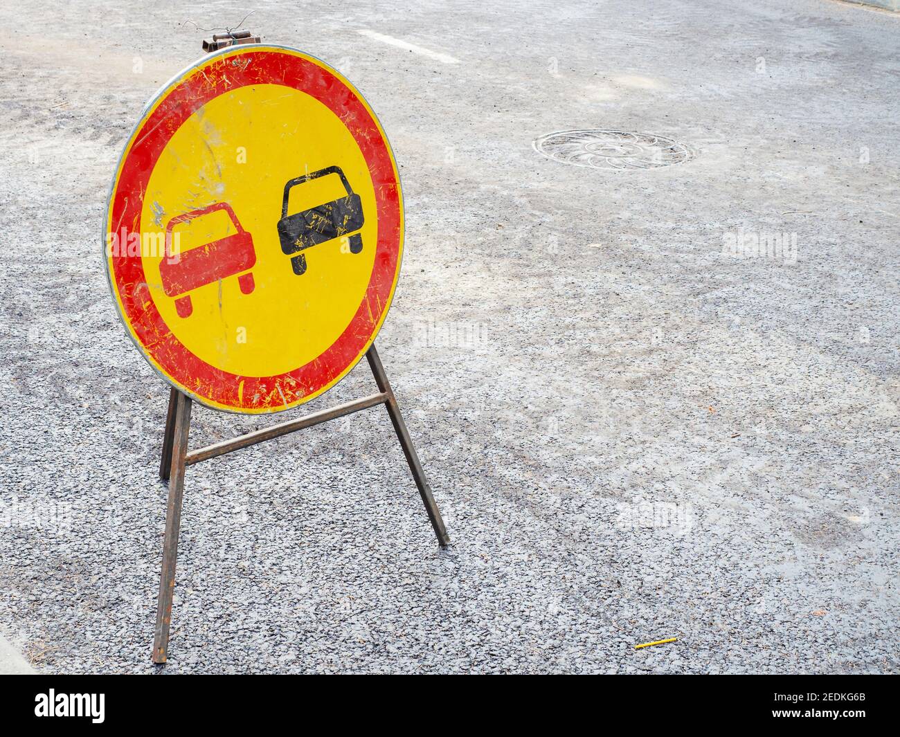A round orange road sign with sketched cars stands on a road prepared ...