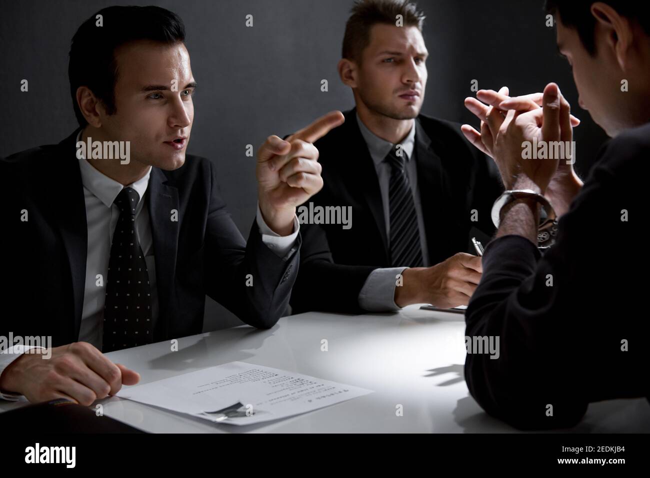 Criminal man with handcuffs being interviewed in interrogation room ...