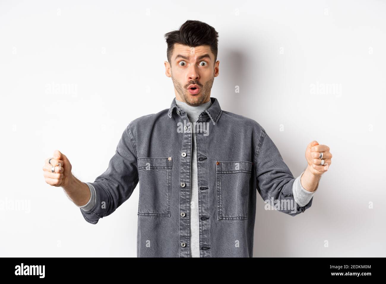 Confused man holding big size object and looking shocked, shaping large ...