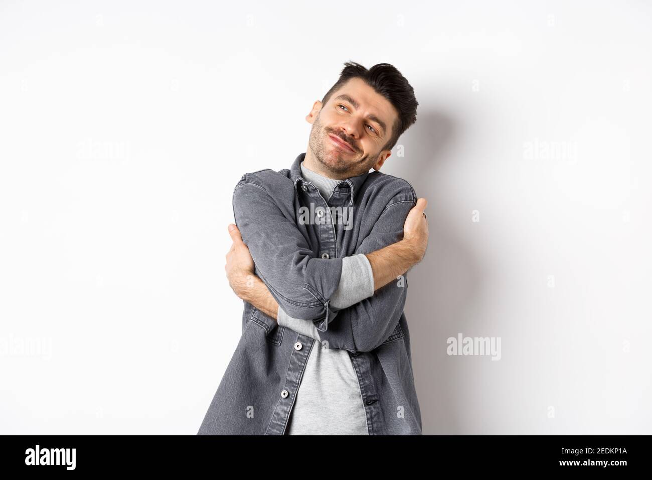Happy romantic guy hugging himself with closed eyes and smile, loving ...