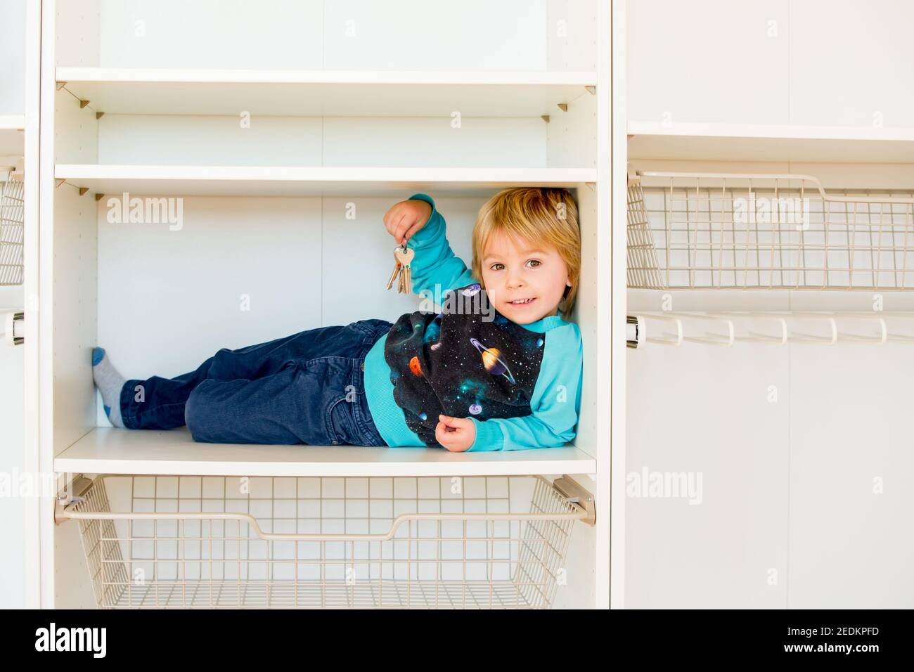 Cute child, sit in a white box in open wardrope, making funny faces ...