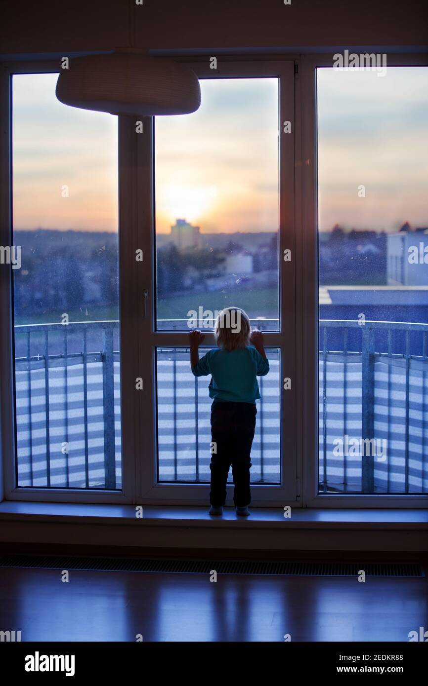 toddler child, sitting on the window on sunset, looking out Stock Photo ...