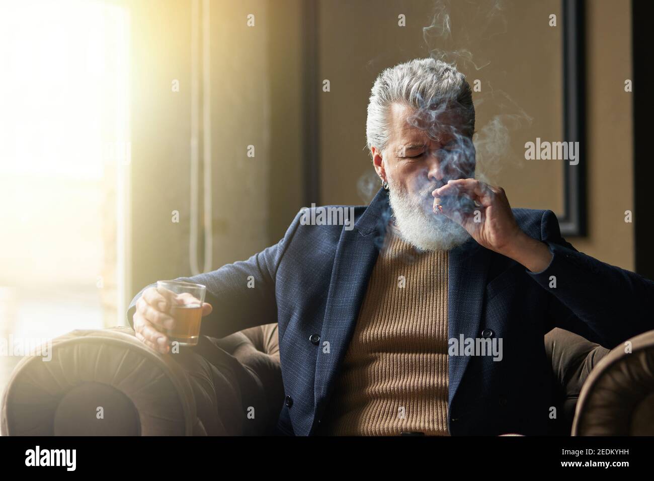 Portrait of elegant mature businessman smoking cigar and drinking ...