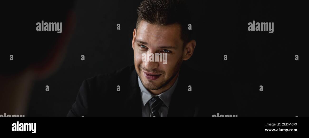 Man in formal business suit staring at interlocutor in shadow, criminal ...