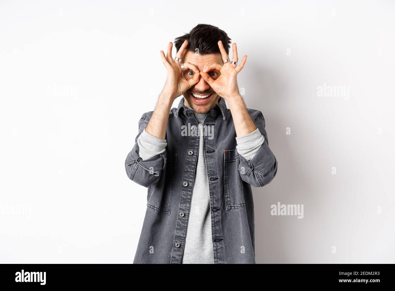 Funny smiling man seeing good offer through hand binoculars, looking ...