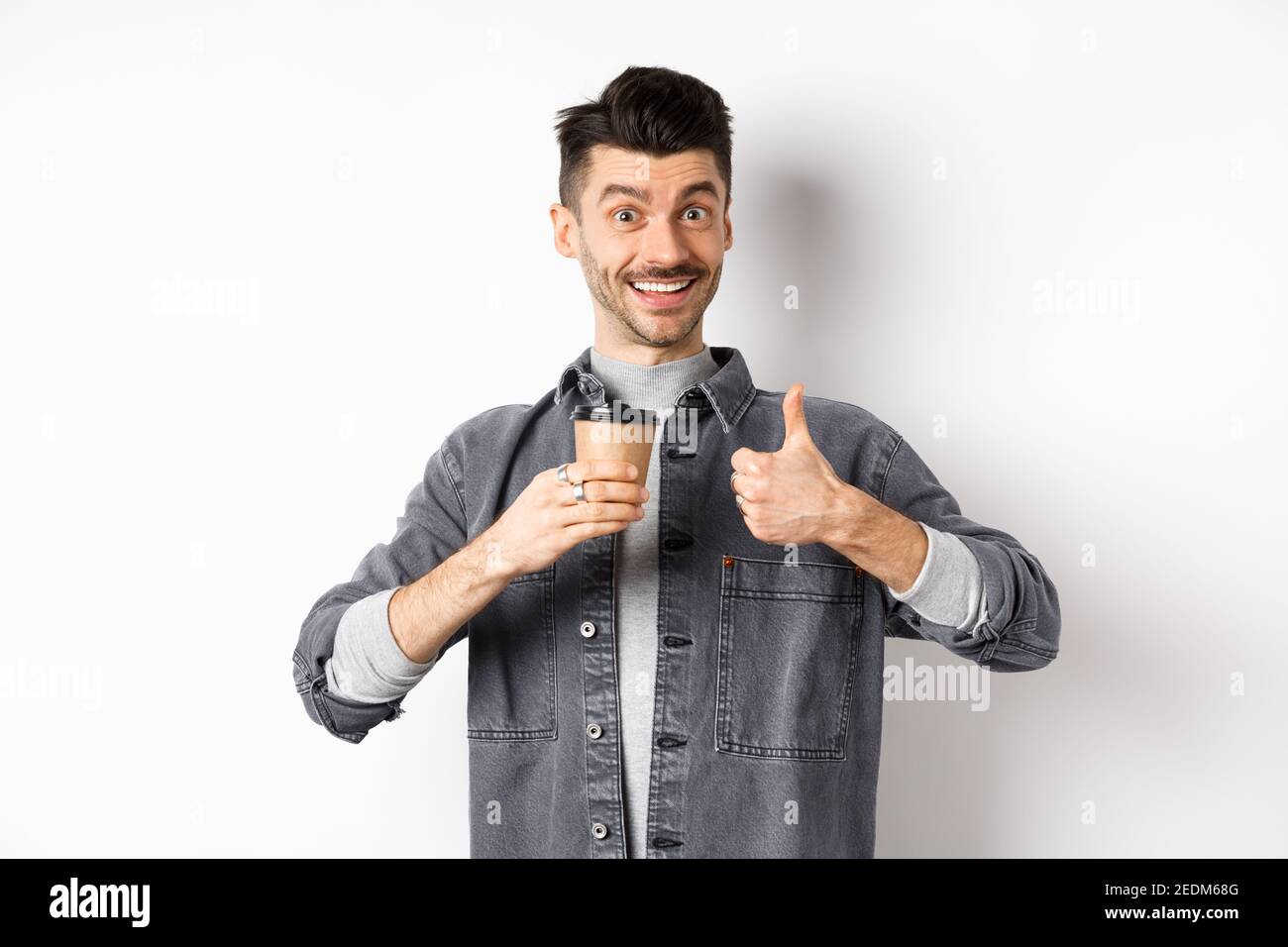 Very good drink. Smiling stylish guy drinking coffee and showing thumbs ...