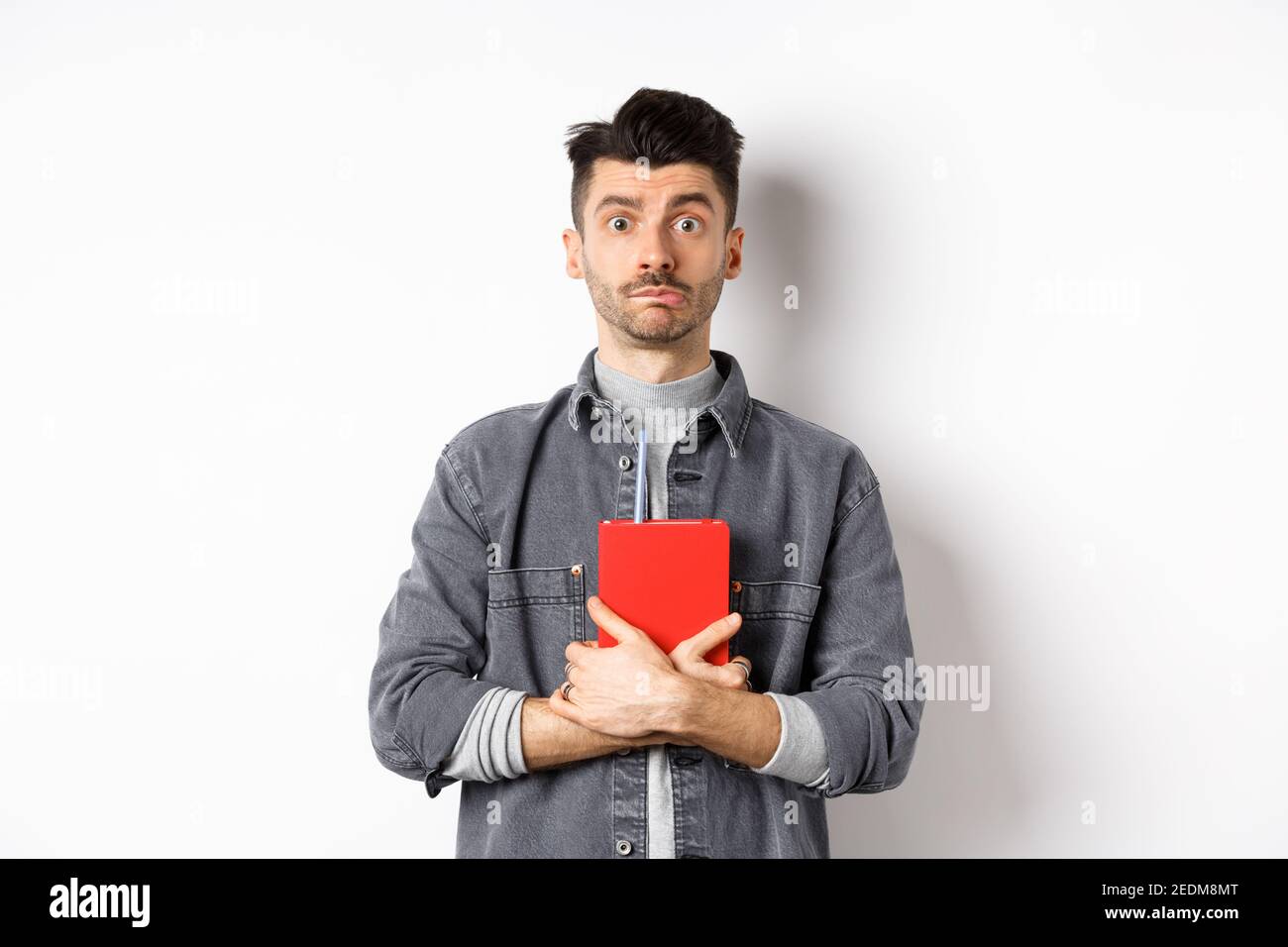Cute and shy guy hugging his diary, holding red journal and look modest ...