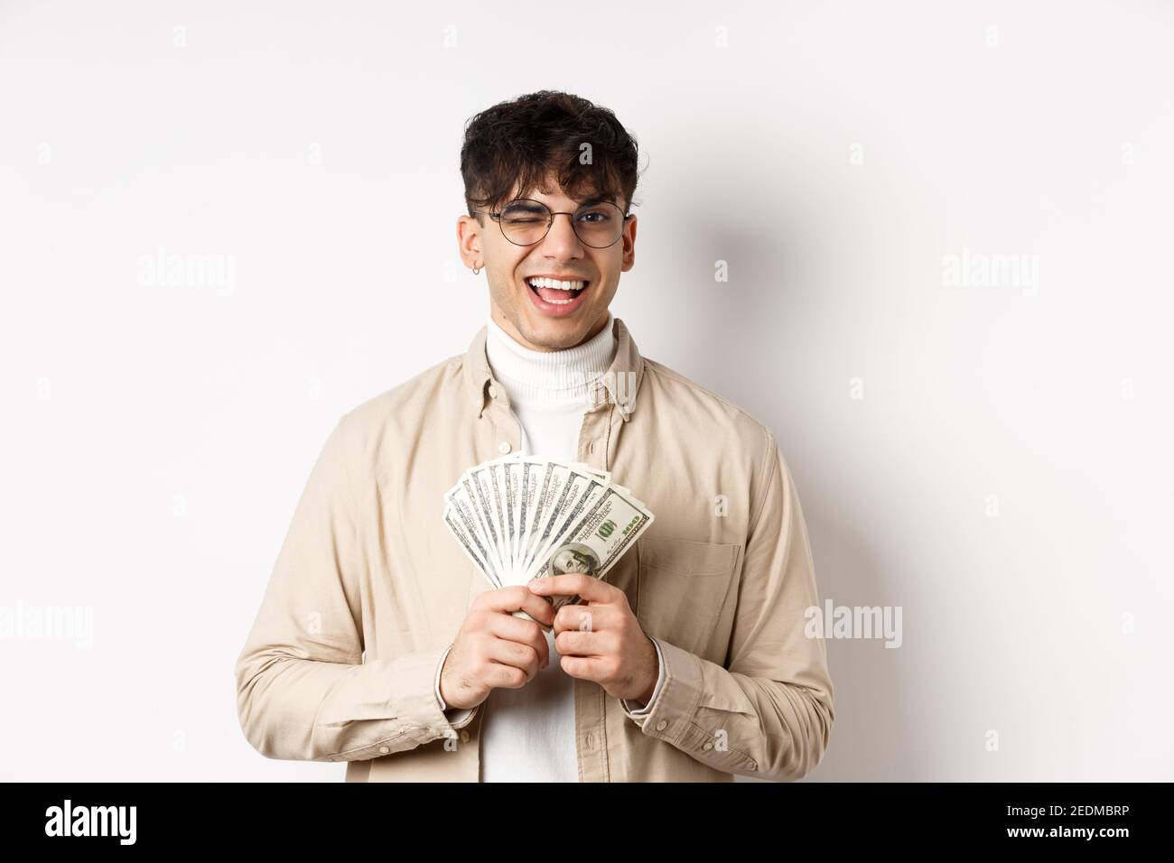 Handsome young man winking and showing dollar bills, holding fan of ...