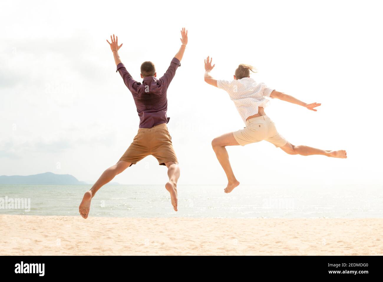 Young energetic happy tourist men jumping at the beach on summer ...