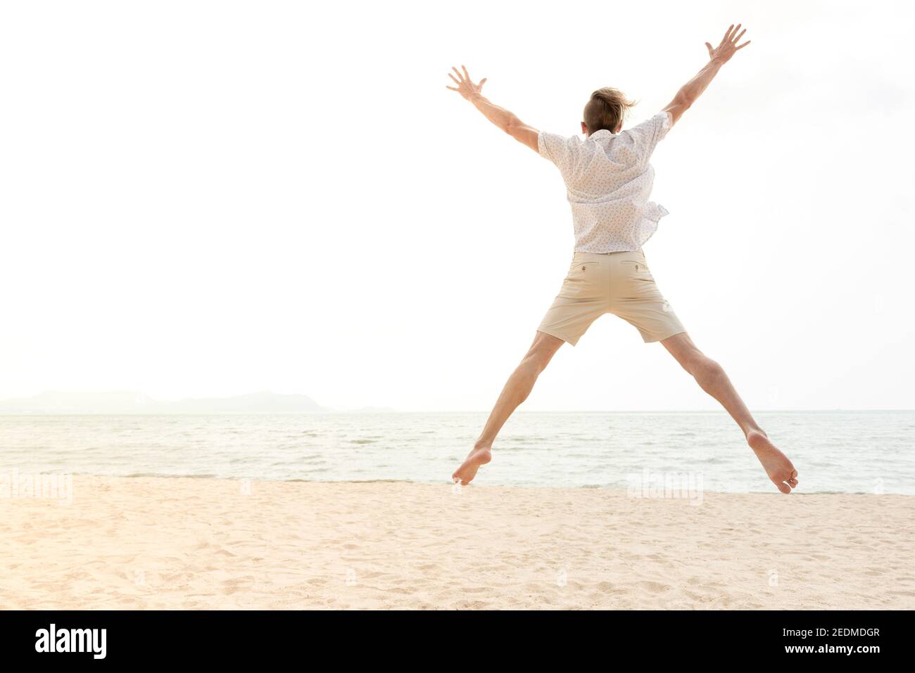 Young energetic happy tourist man jumping at the beach on summer ...