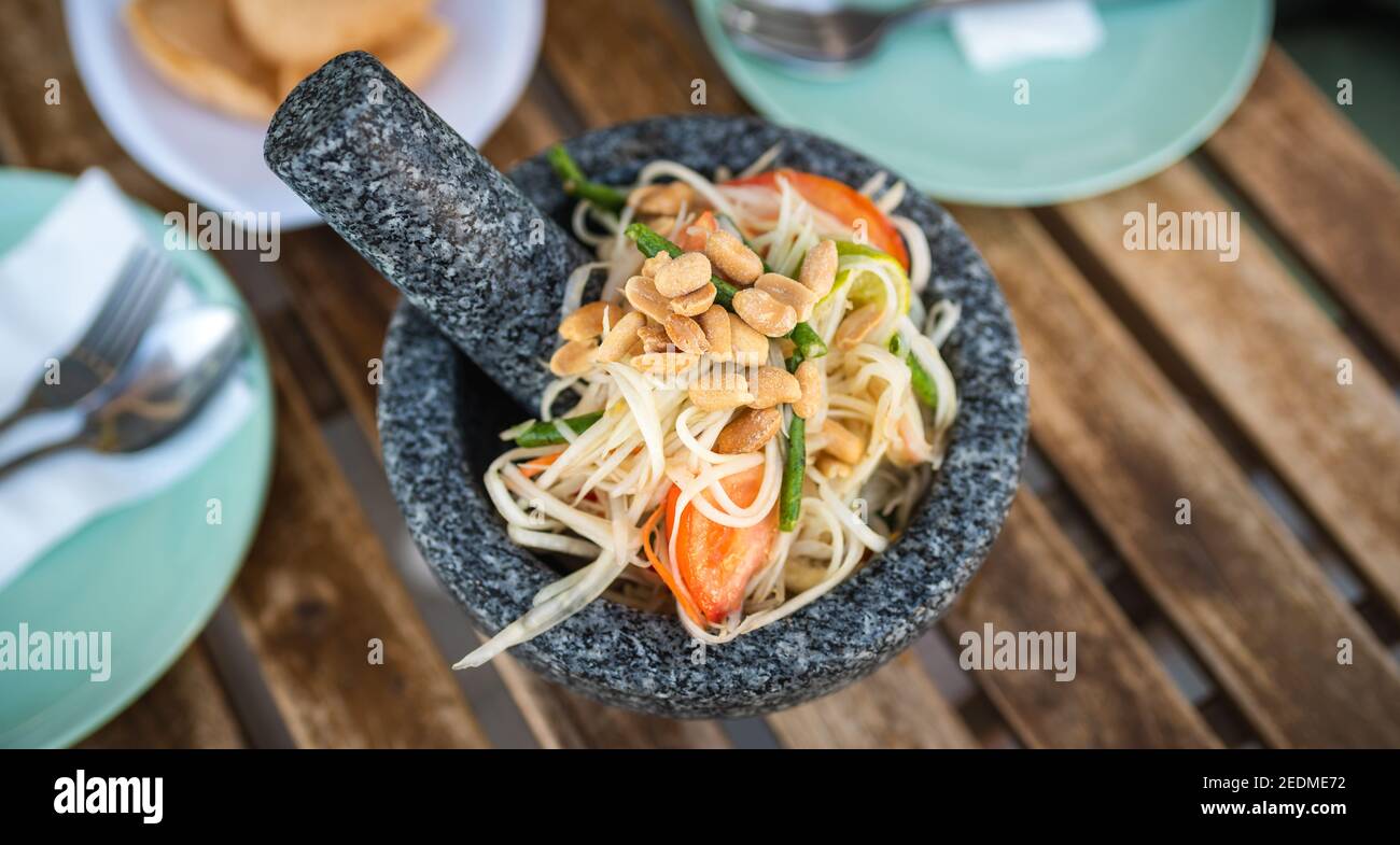 Thai green papaya salad called som tam or som dam on a plate top view ...
