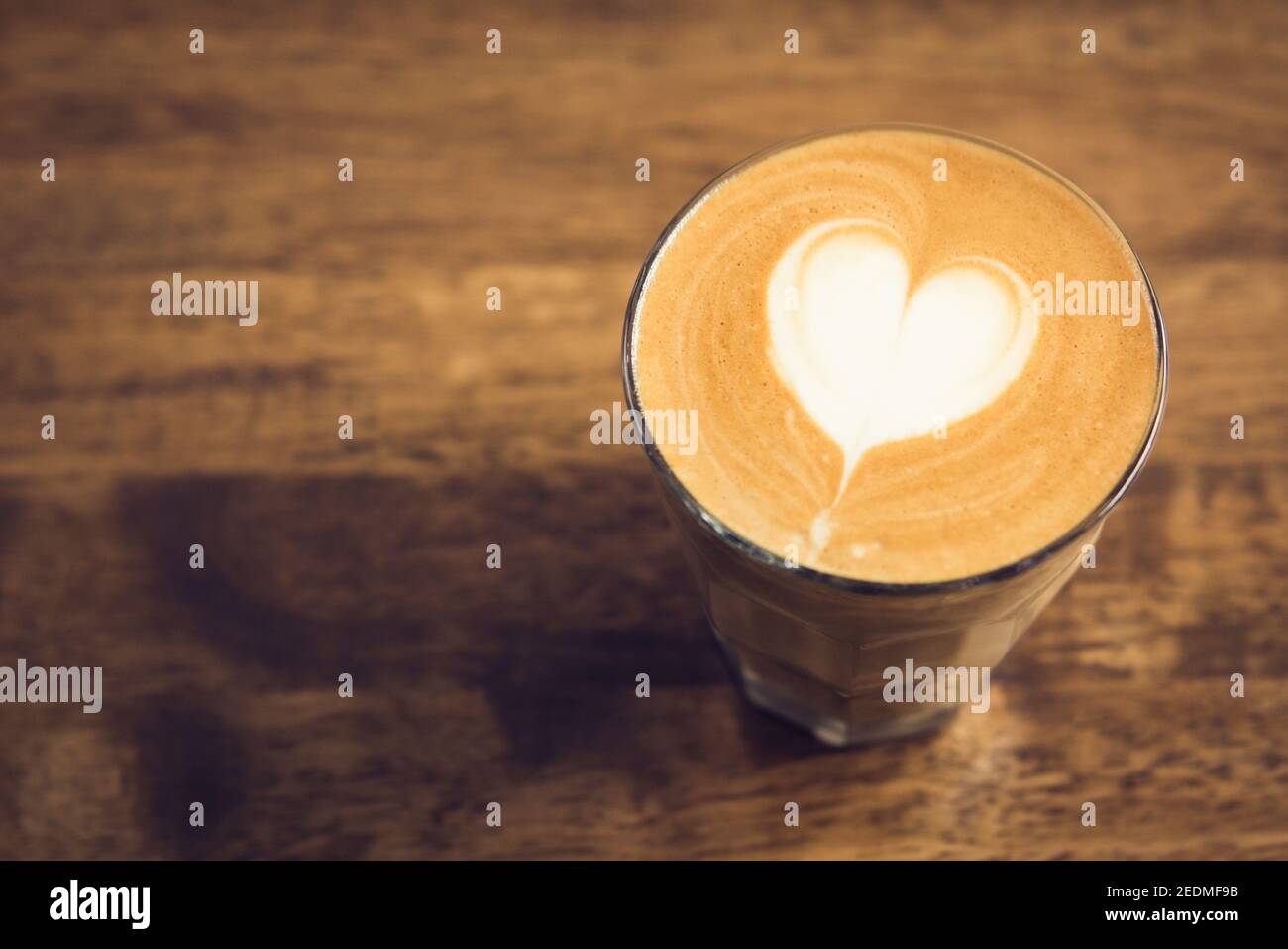 Beautiful heart shape latte art coffee in the glass on wood table with ...