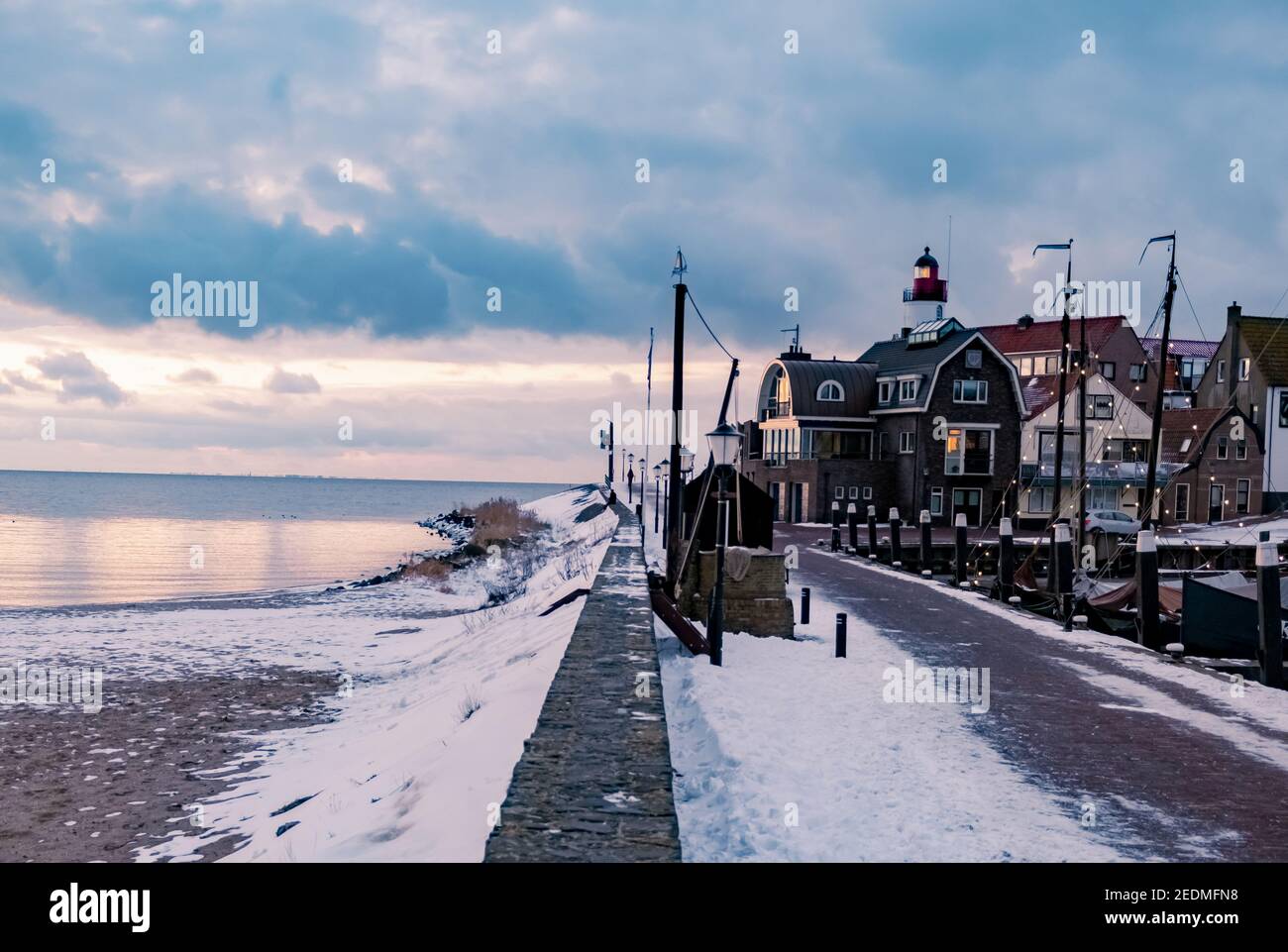snow covered beach during wnter by Urk lighthouse in the Netherlands ...