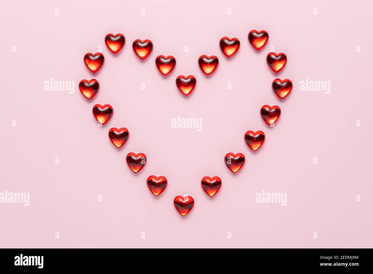 Heart shape made with small glass hearts over pink background. Minimal ...