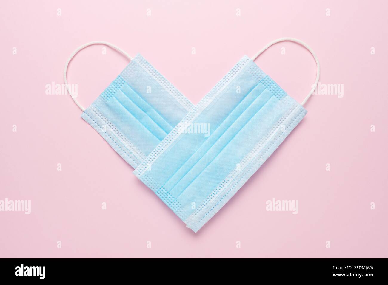 Heart shape made by medical masks on pink background. Creative minimal ...