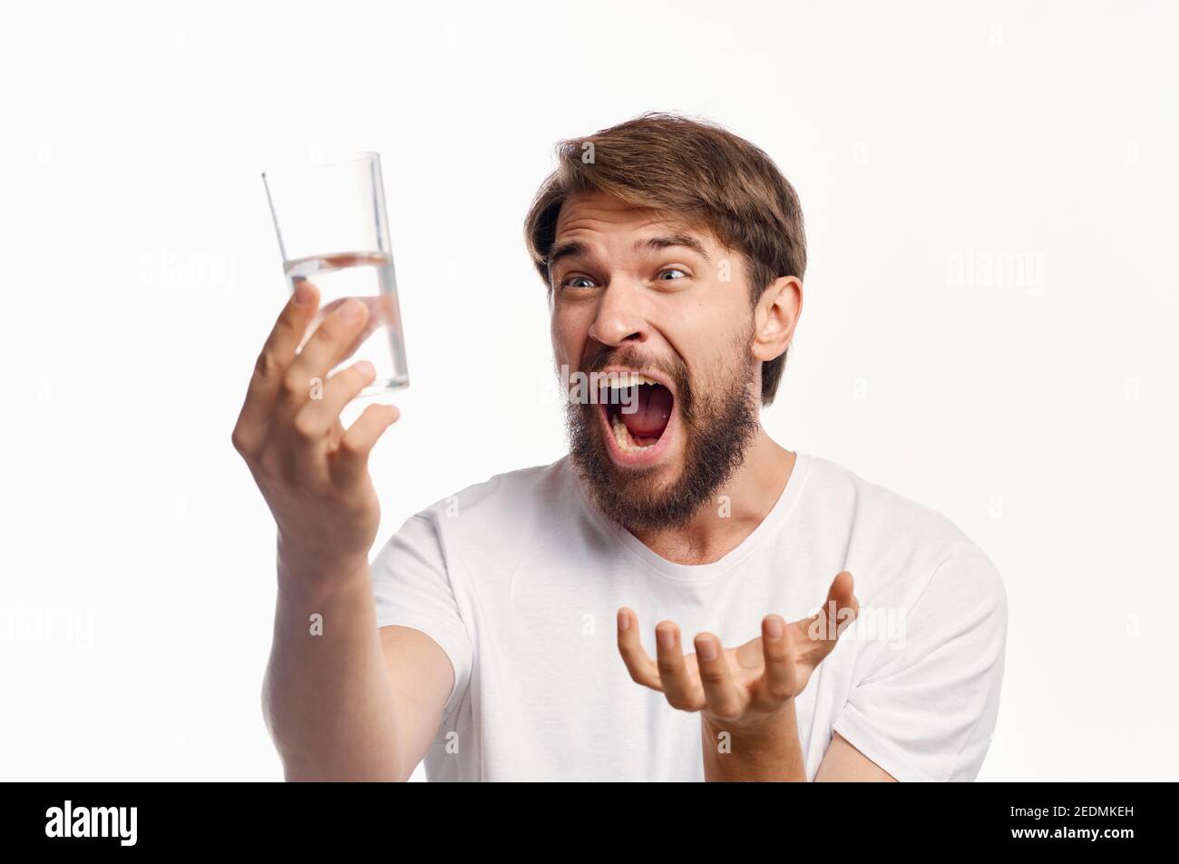 aggressive man examines clear water in a glass on a white background ...