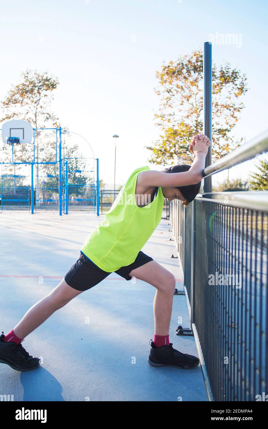 Young basketball player stretching legs before playing game outdoors ...
