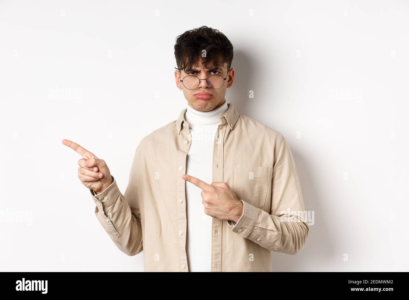 Sad and grumpy boy pointing fingers left, sulking with childish ...