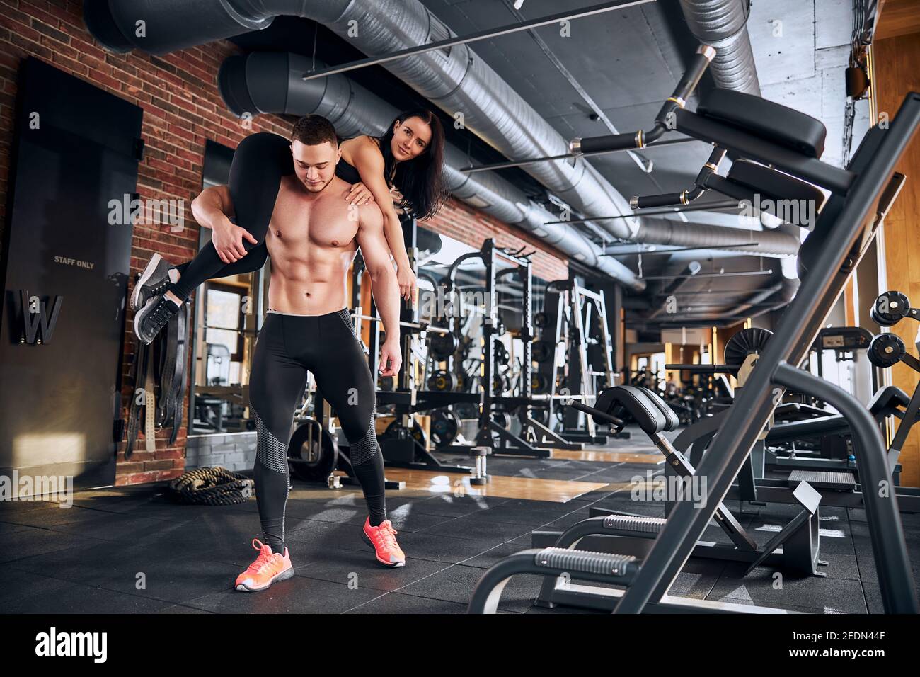 Strong bodybuilder carrying girlfriend on shoulders during training ...