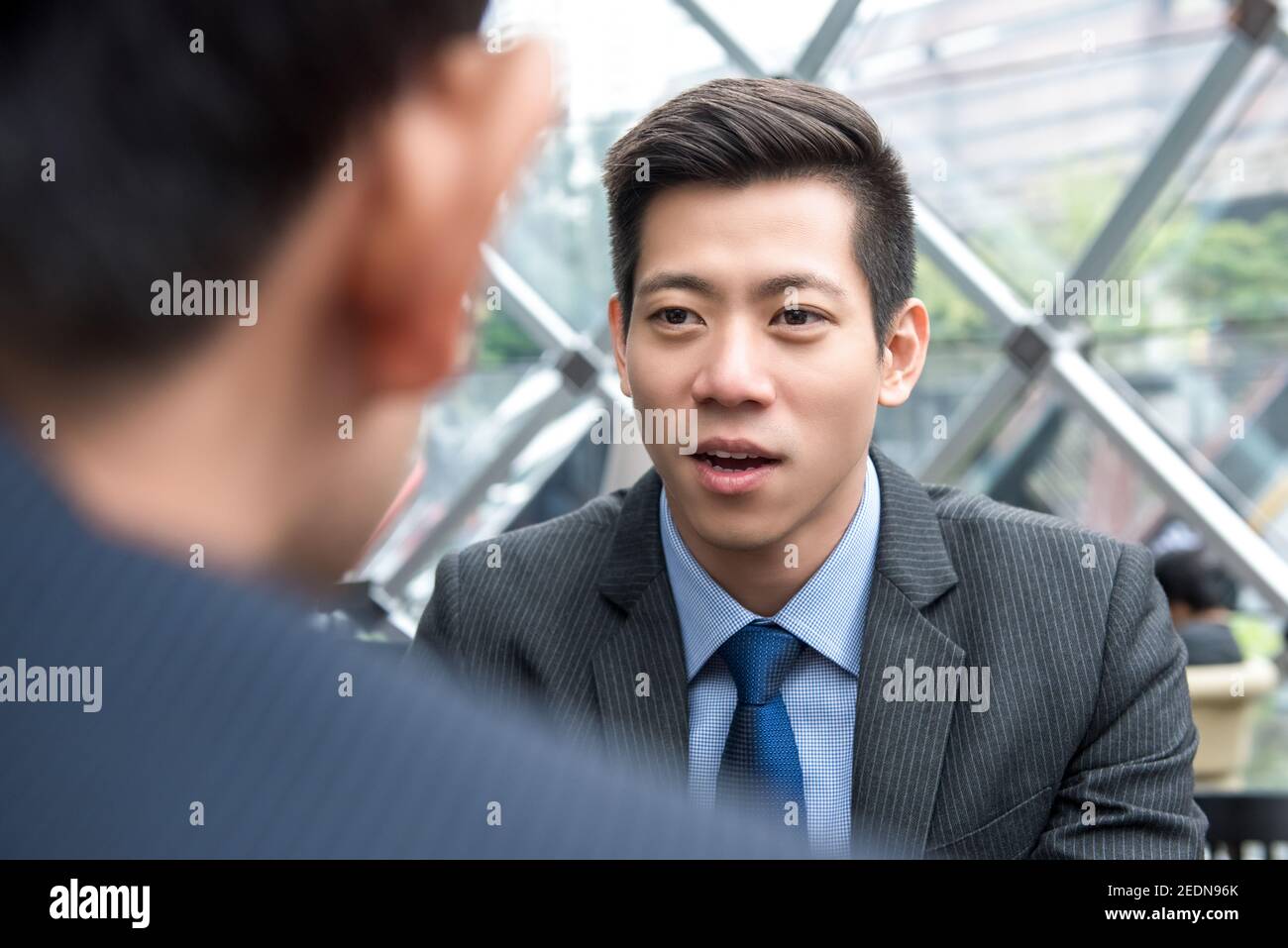 Young handsome Asian Chinese businessman talking to his partner with ...