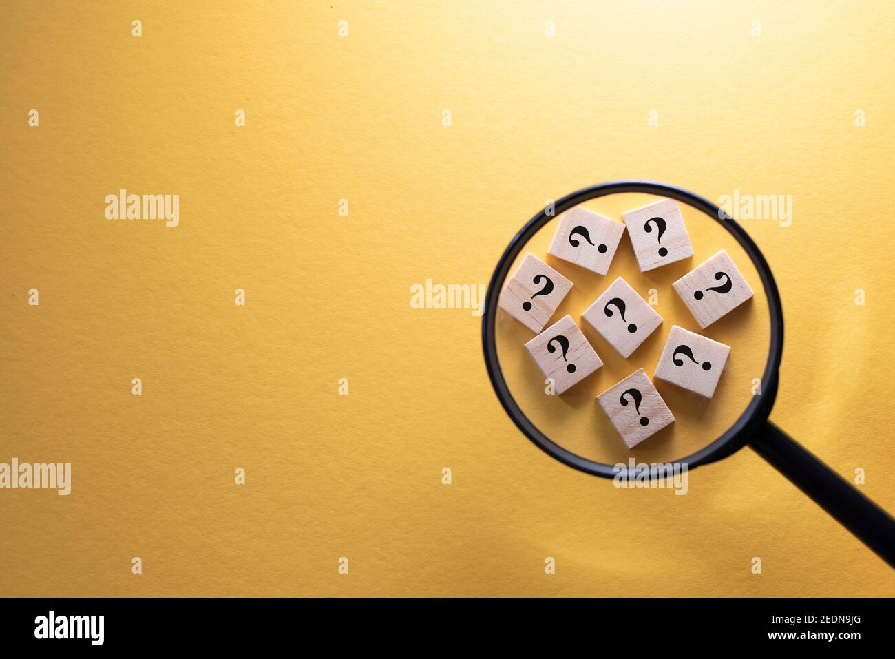 Focus on Question Mark symbol on a wooden tiles using magnifying glass ...