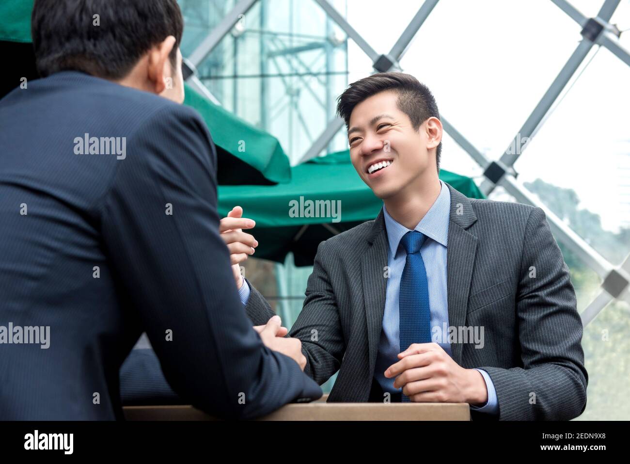 Young Asian business partners happily talking at cafe Stock Photo - Alamy
