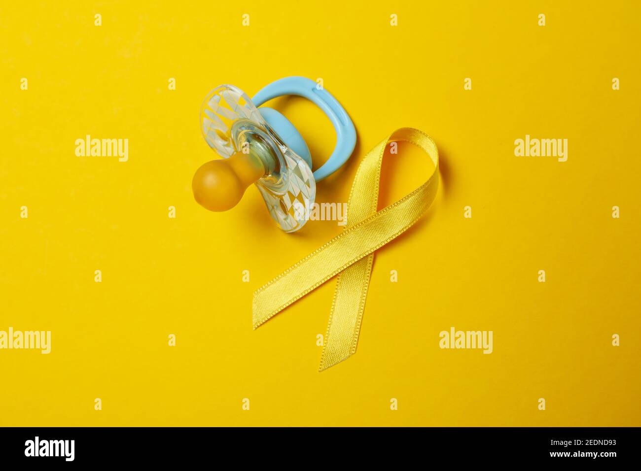 Pacifier and child cancer awareness ribbon on yellow background Stock ...