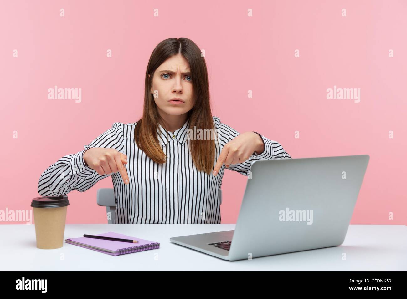 Strict woman boss in striped shirt sitting at workplace with laptop ...
