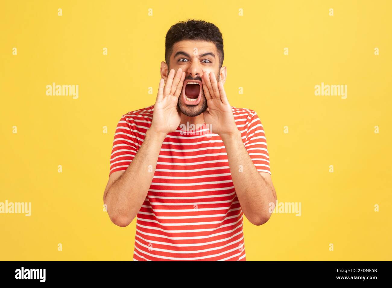 Angry nervous bearded man in striped t-shirt loudly yelling widely ...