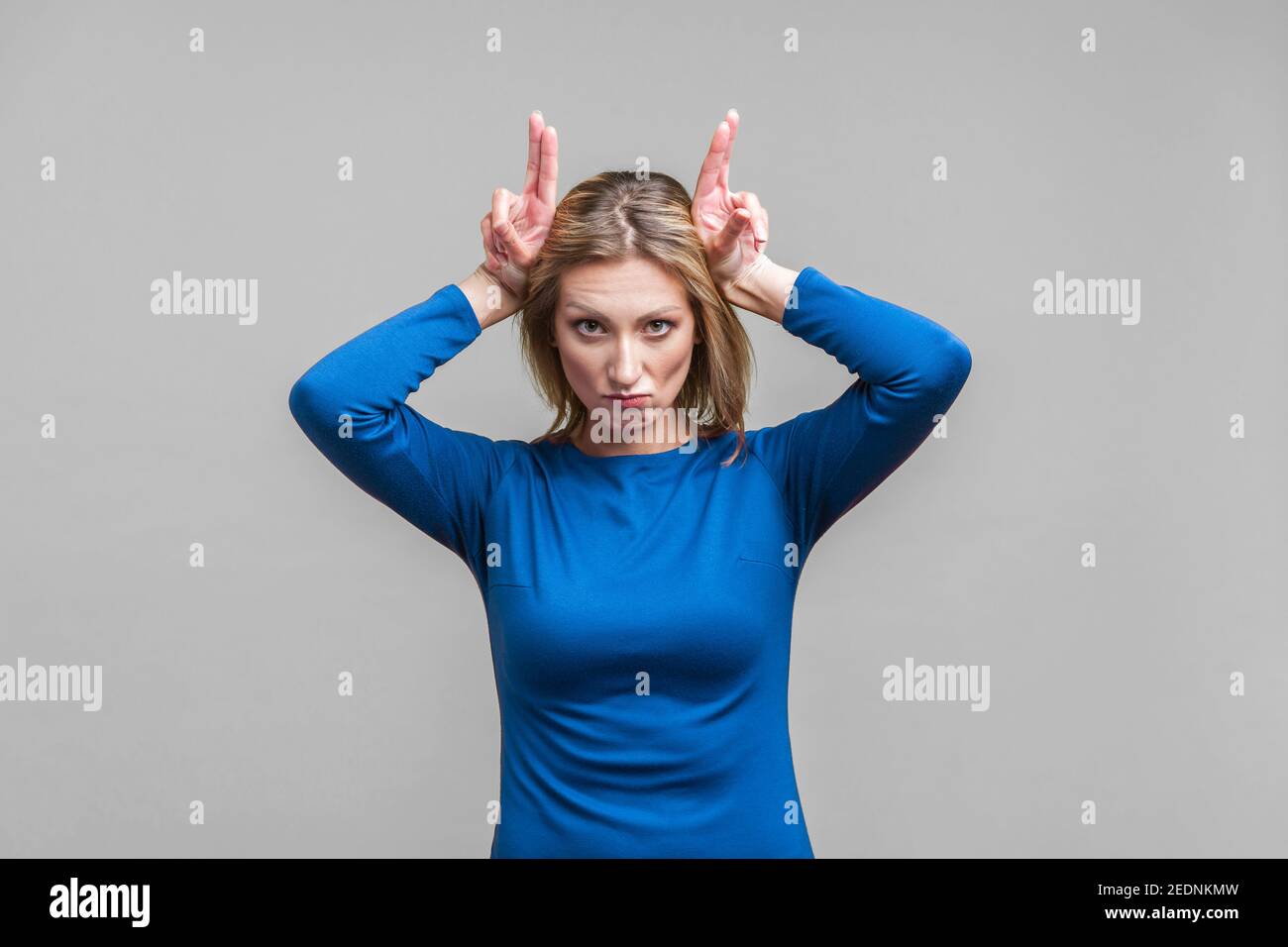 Portrait of bully woman in elegant tight blue dress looking threatening ...