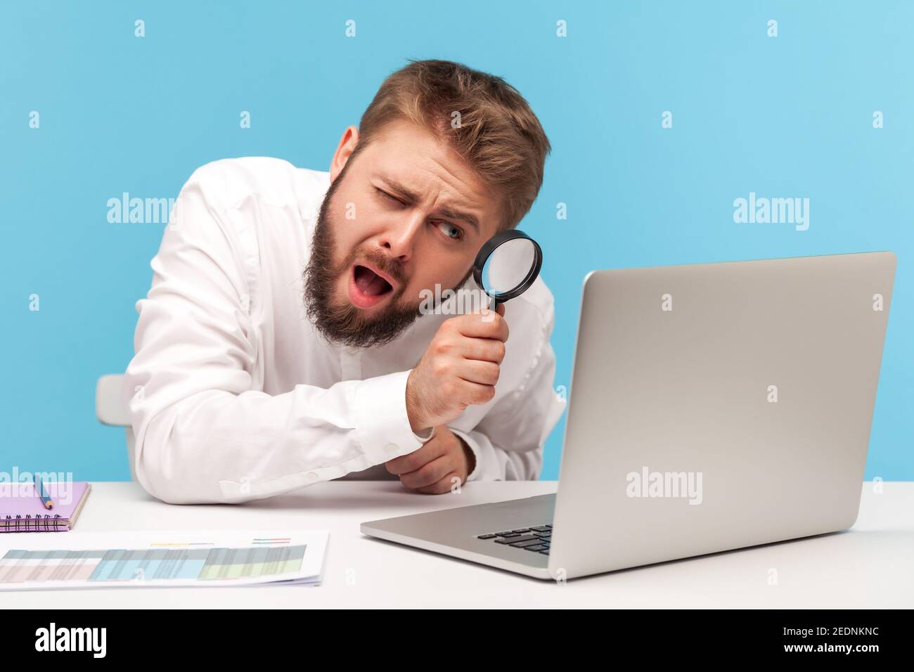 Curious man office worker looking at laptop display through loupe ...