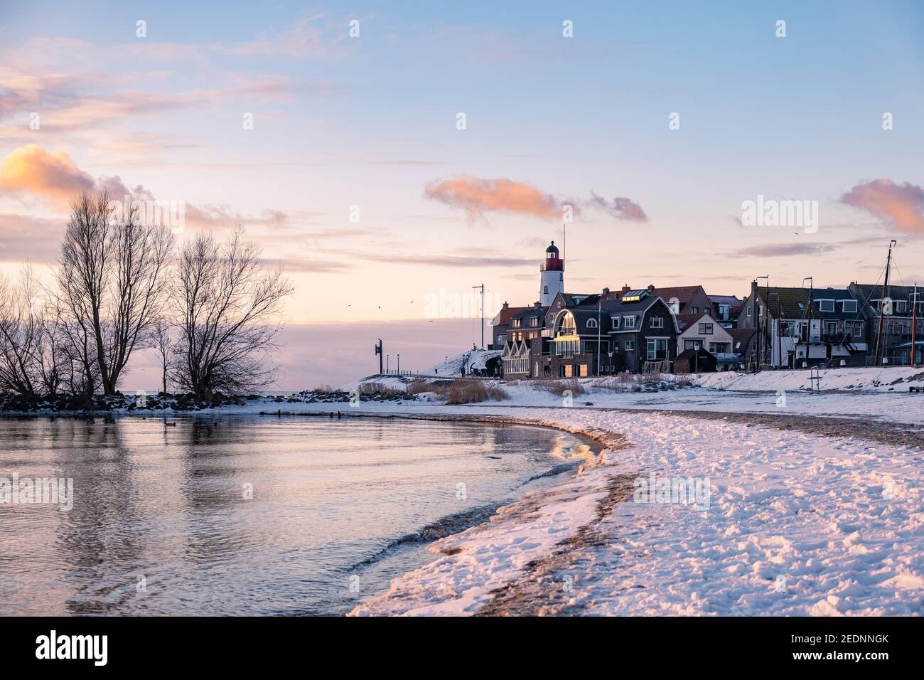 snow covered beach during wnter by Urk lighthouse in the Netherlands ...