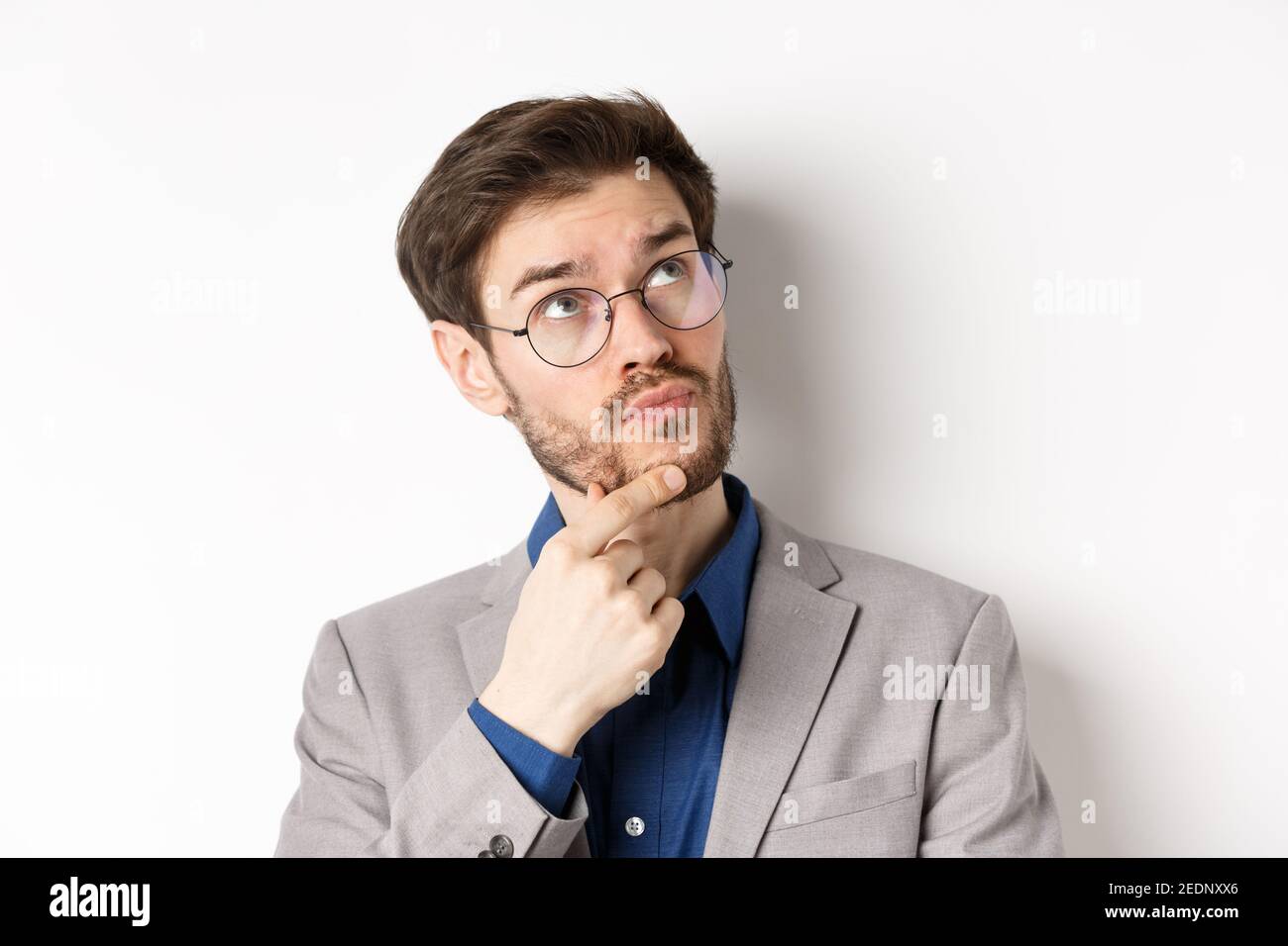 Thoughtful businessman with beard and glasses making decision, looking ...