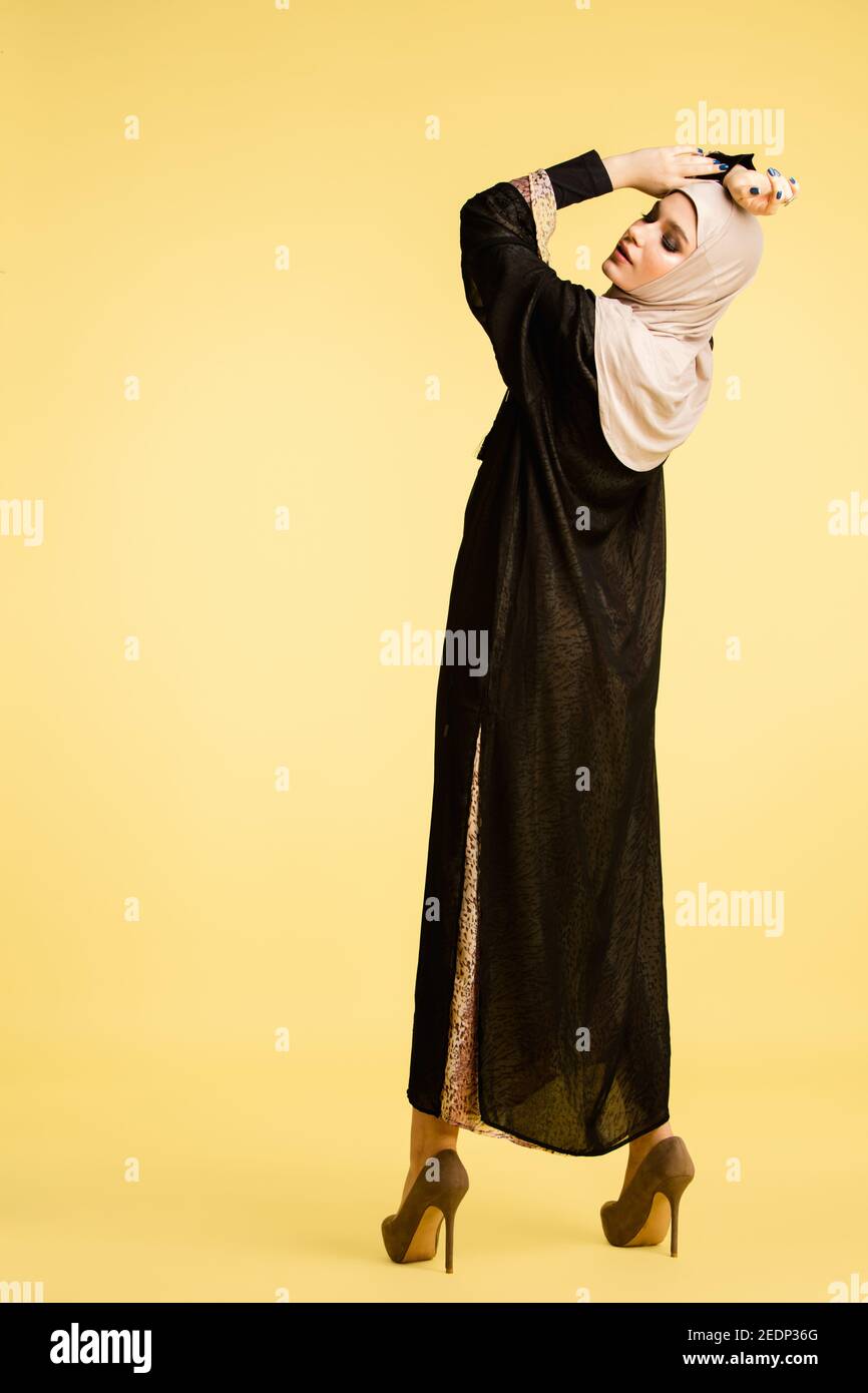 Posing. Beautiful young arab woman in stylish hijab isolated on yellow ...