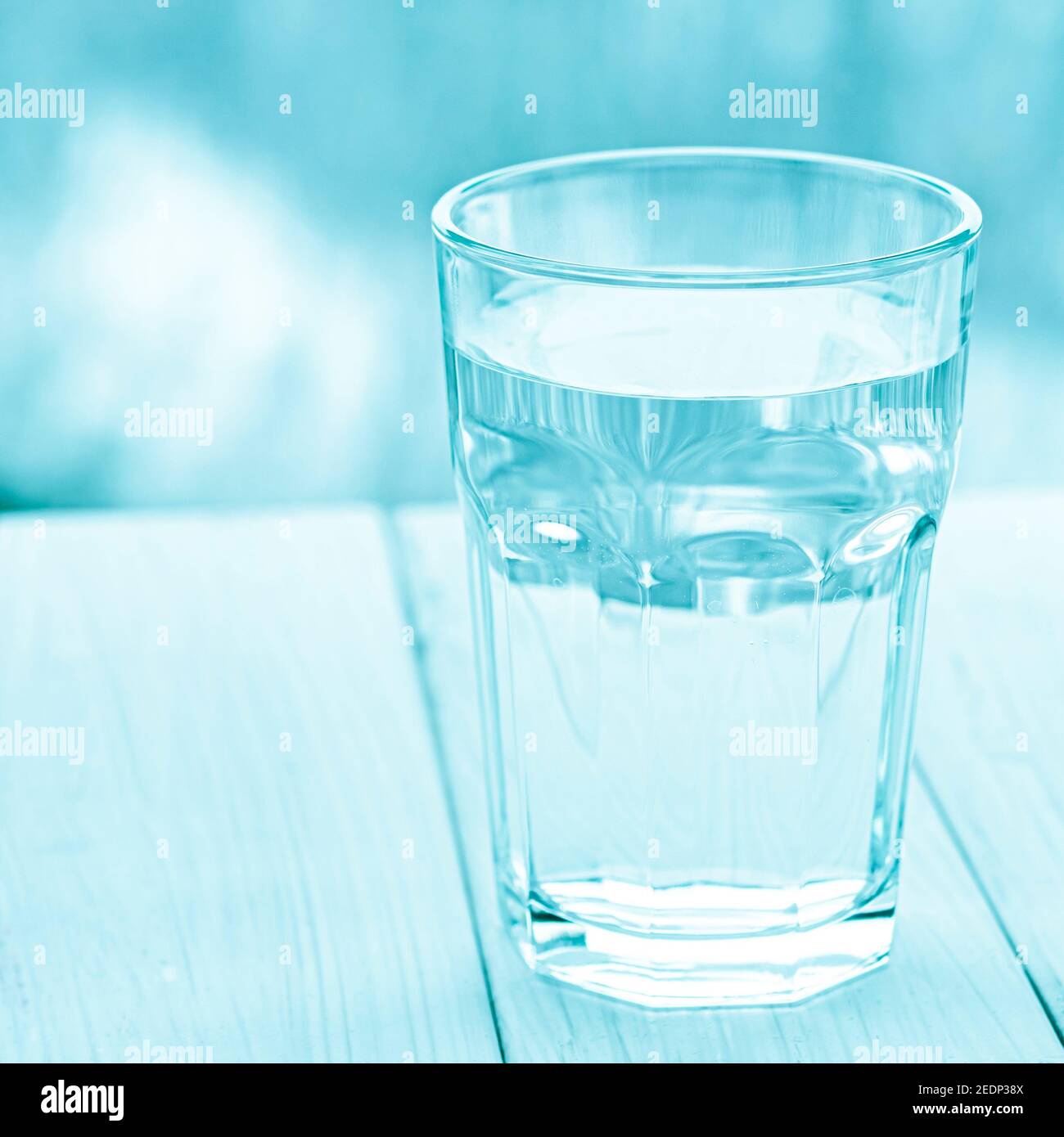 A glass with pure clear melt water stands on a white wood table Stock ...