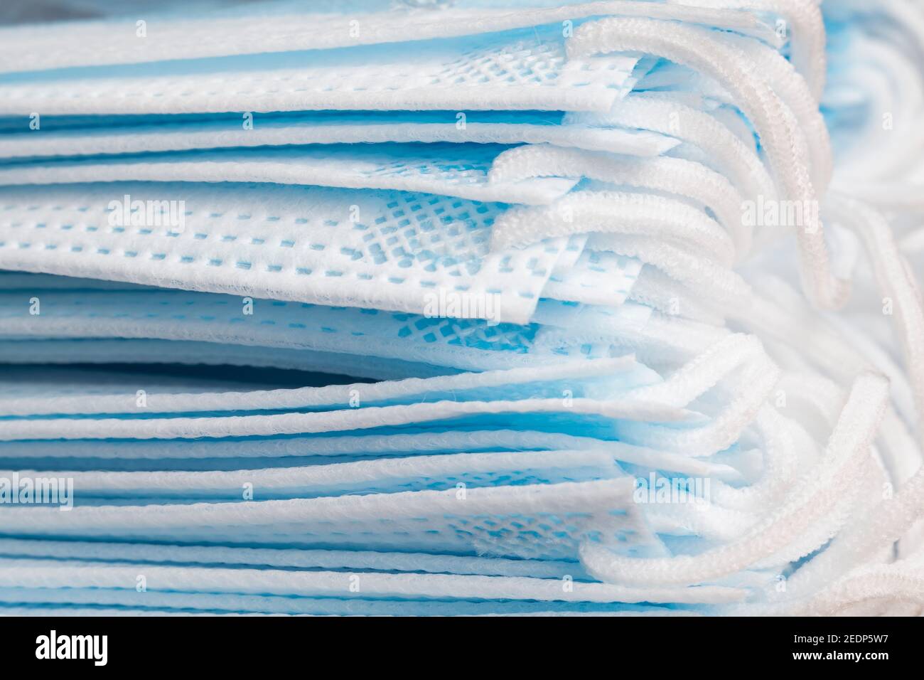 Lot of white-blue medical masks with strings are stacked in a pile ...