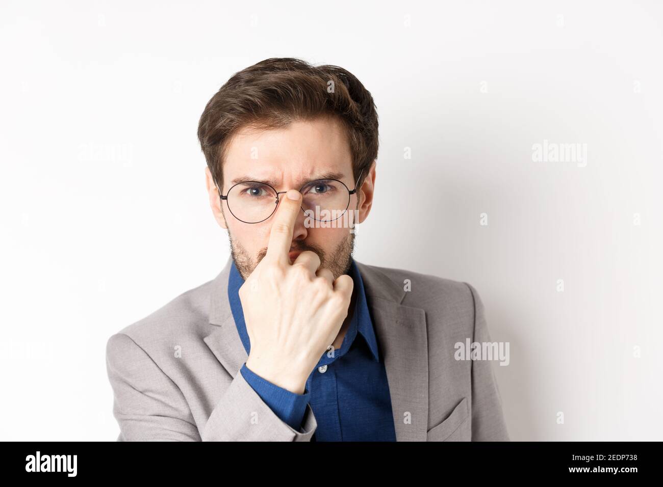 Serious boss in suit frowning, put on glasses and looking suspicious at ...