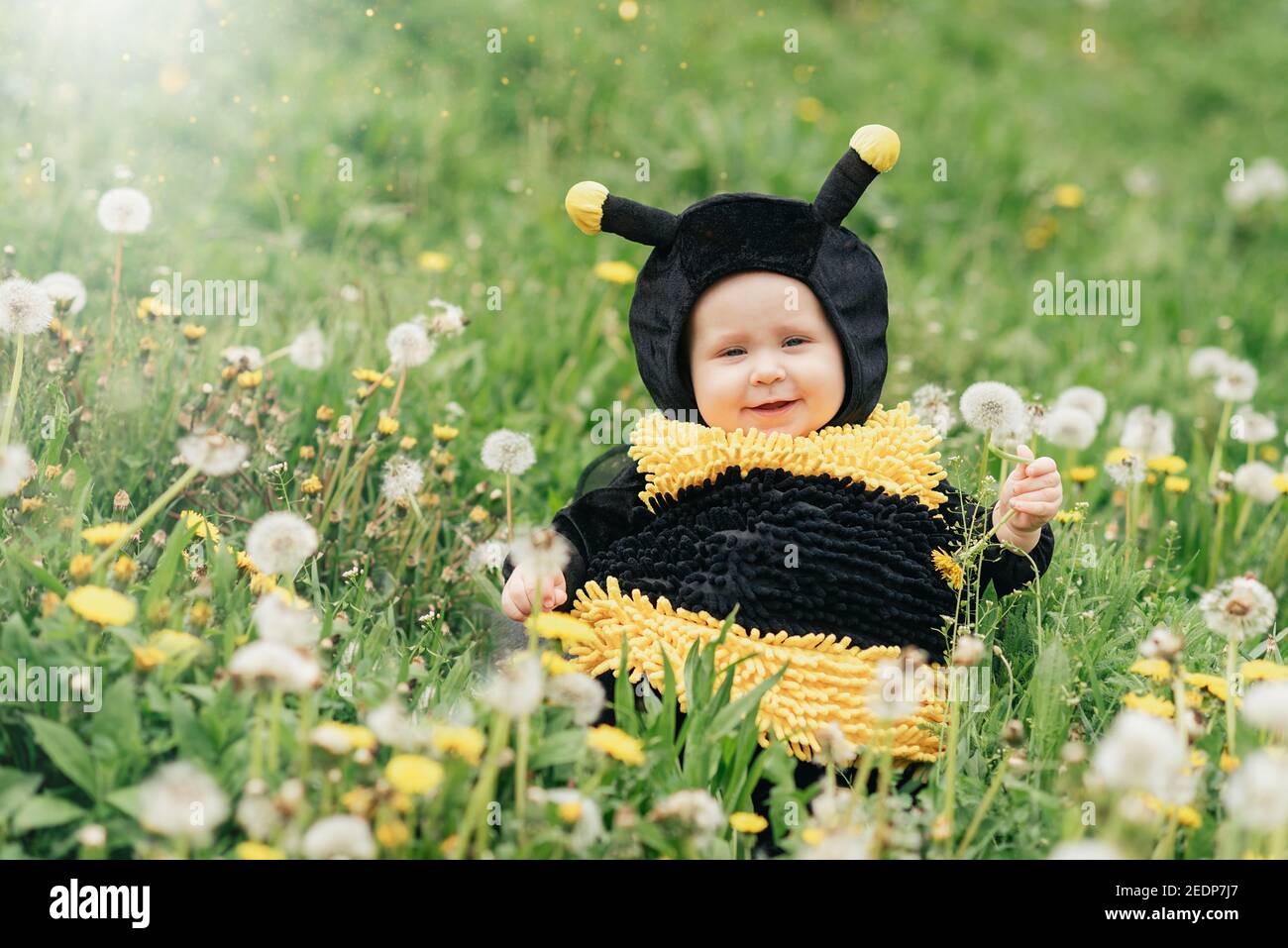 cute and cheerful portrait of little child sitting in blooming flowers ...