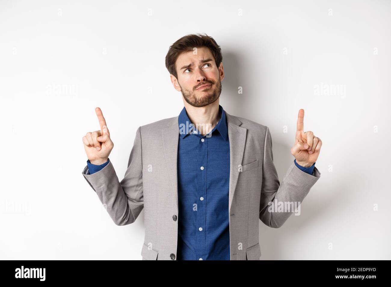Skeptical and hesitant young businessman in suit looking up with ...