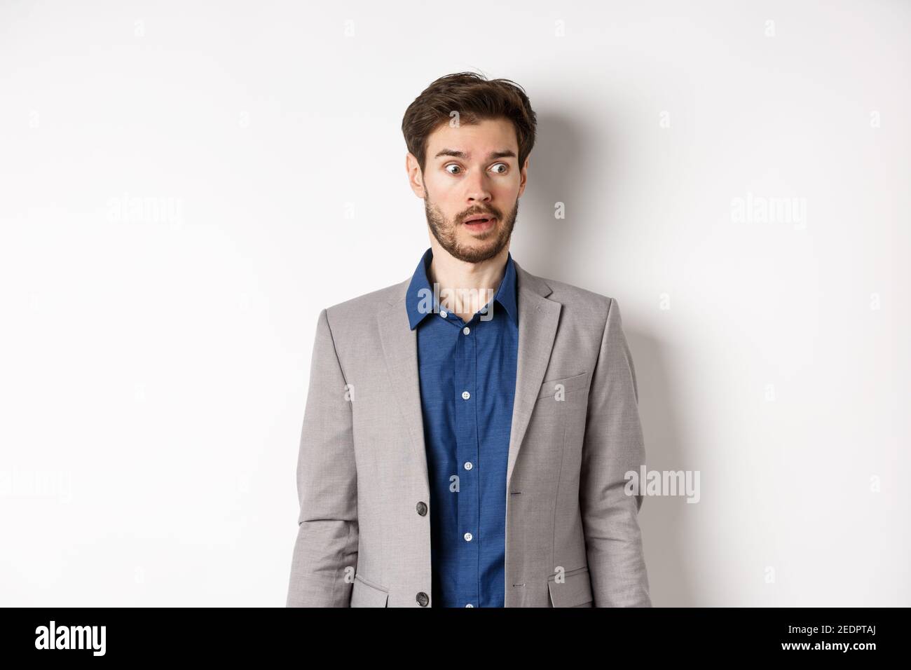 Shocked male entrepreneur in suit looking aside at logo with startled ...