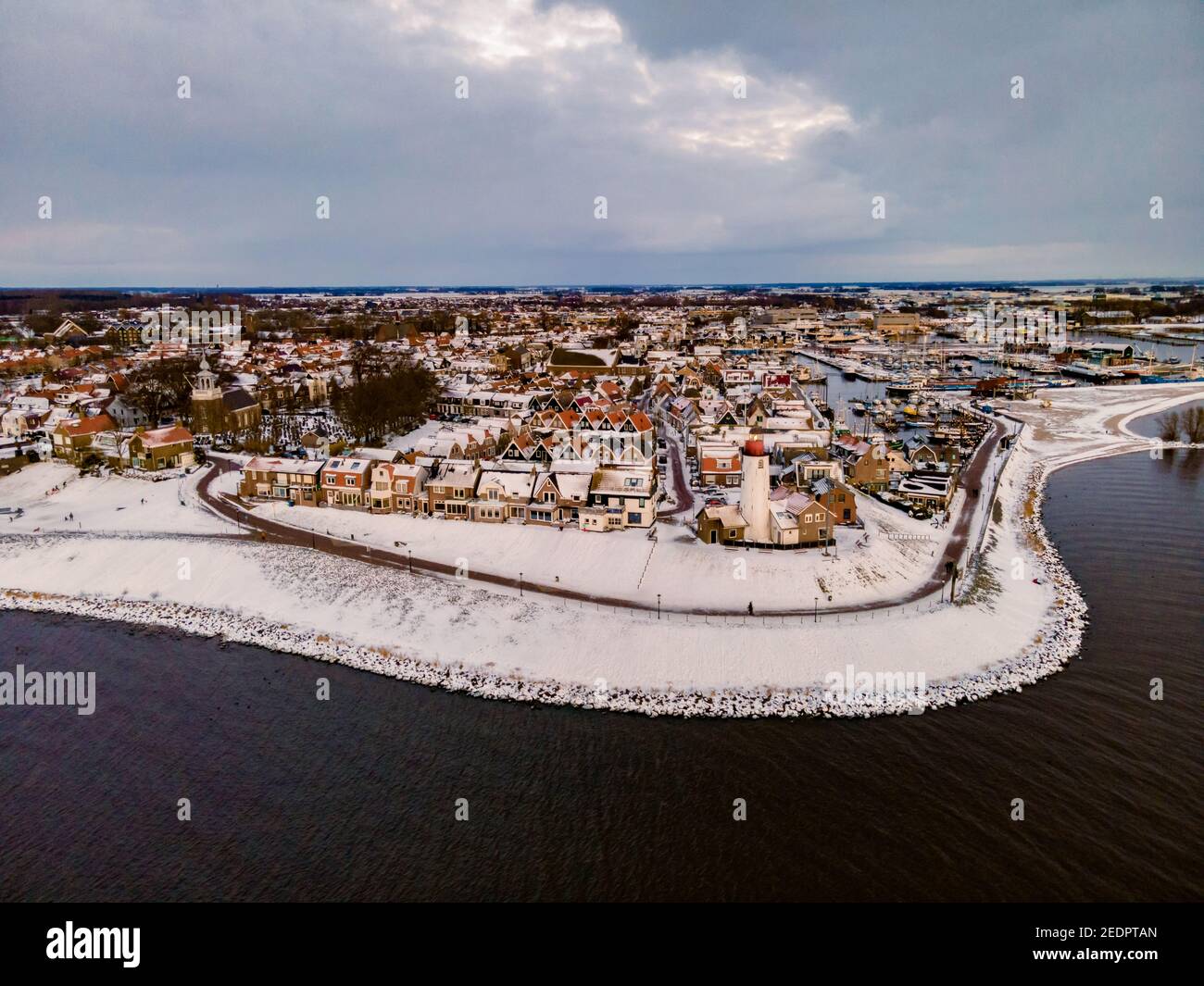 snow covered beach during wnter by Urk lighthouse in the Netherlands ...