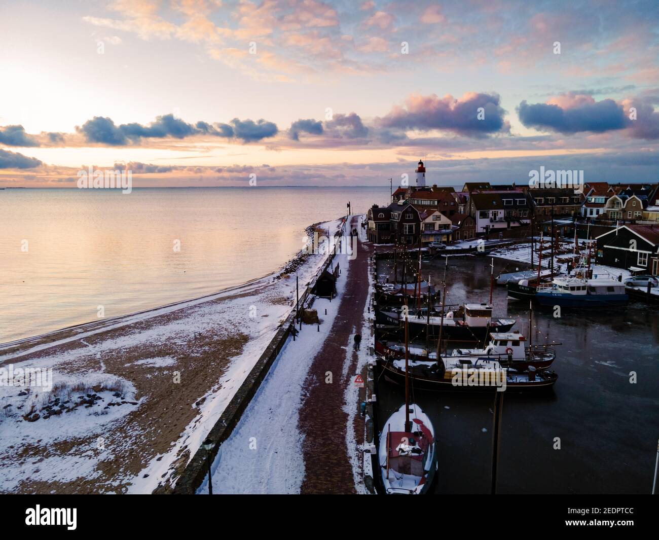 snow covered beach during wnter by Urk lighthouse in the Netherlands ...