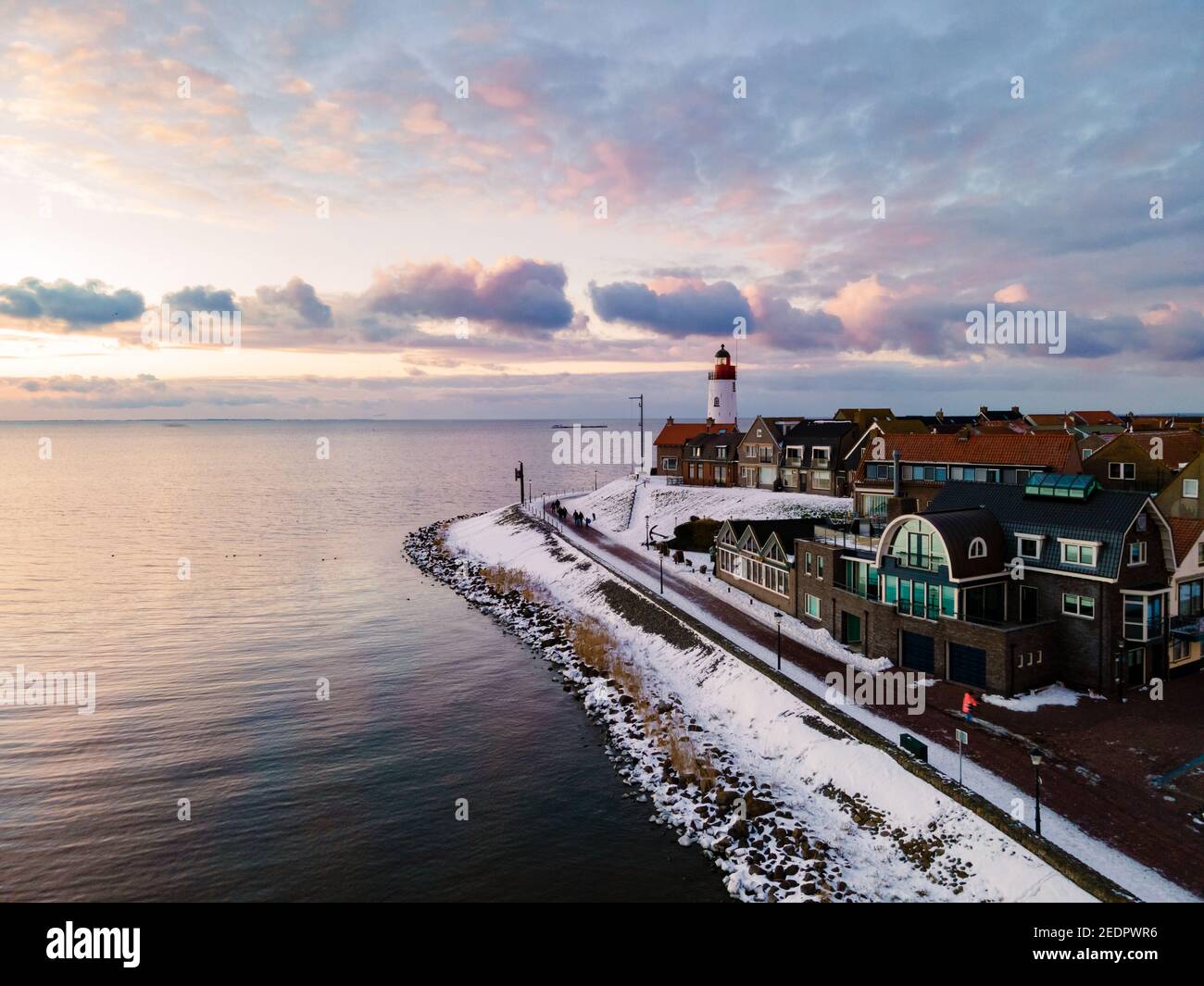 snow covered beach during wnter by Urk lighthouse in the Netherlands ...