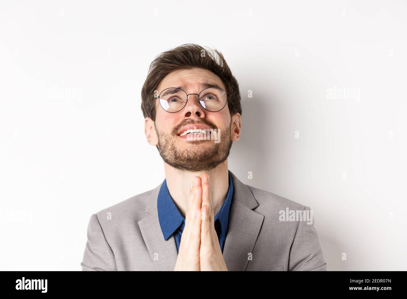 Nervous hopeful man in glasses and suit begging god, asking please and ...